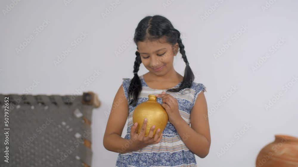 Young village girl happily putting a coin in her money bank - savings ...