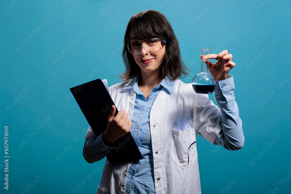 Microbiology expert on blue background holding glass beaker filled with chemical compound ...