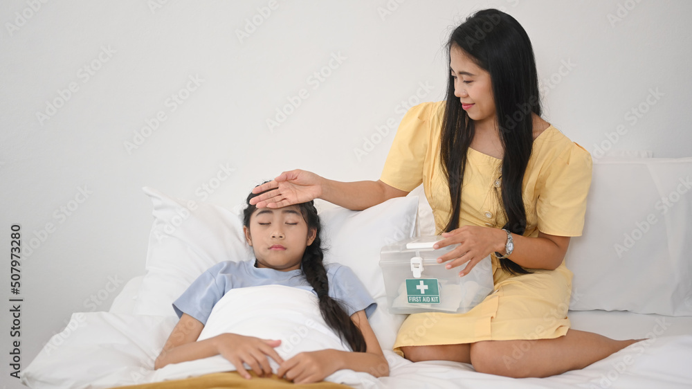 Caring asian mother taking care of sick daughter and checking ...