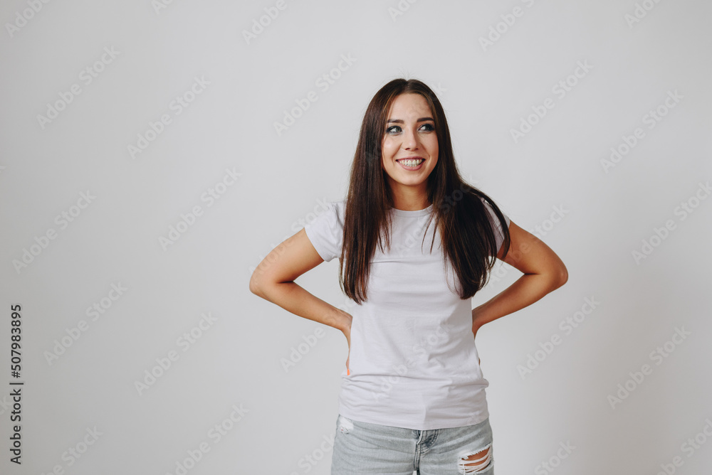 Girl in white T-shirt and jeans poses against a white background as she ...