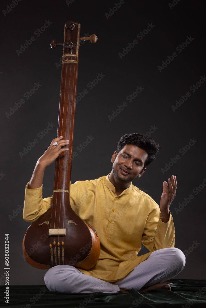 Portrait of young man performing with Tanpura at concert Stock Photo ...