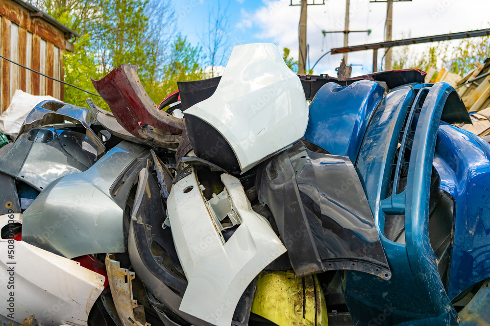 A group of plastic fiber car bumpers in a car junkyard. Plastic raw ...