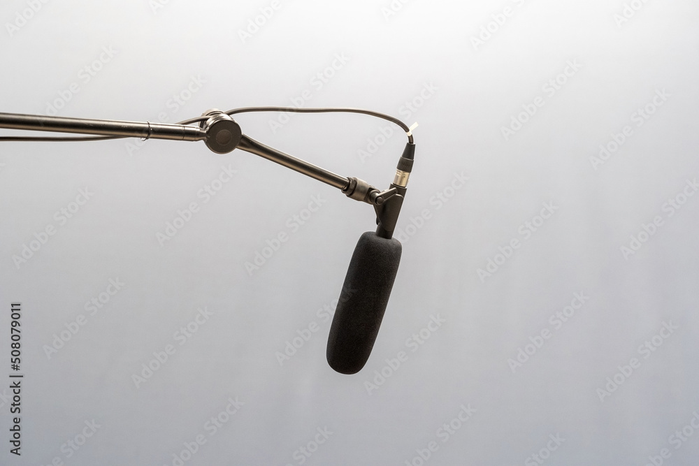 Simple black studio mic, directional microphone hanging placed on a mic ...