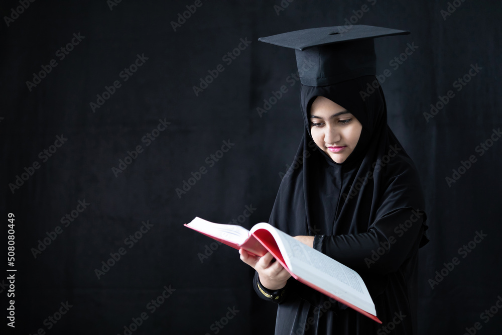 muslim girl with graduation cap and reading a holy book or quran on ...