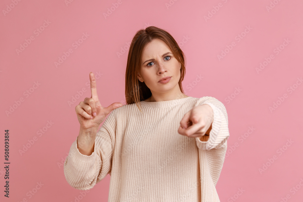 Portrait of serious blond woman pointing finger at you showing loser ...