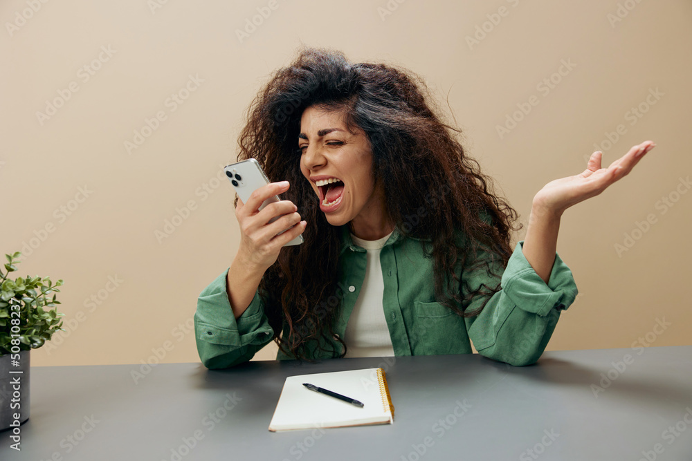 Angry crazy irritated tanned curly Latin lady scream at phone screen ...