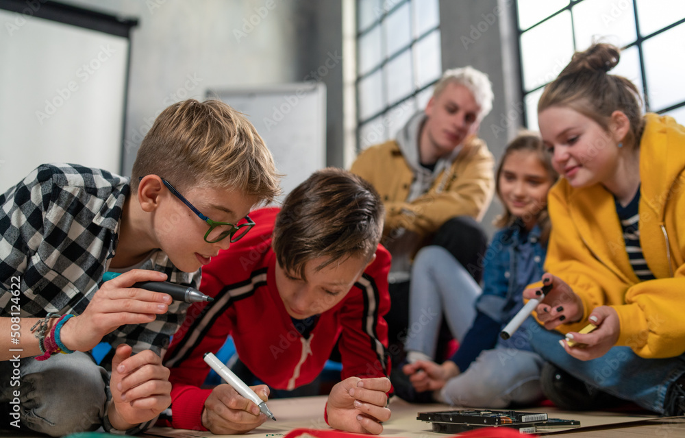 Group of happy kids with their teacher working on project together at ...