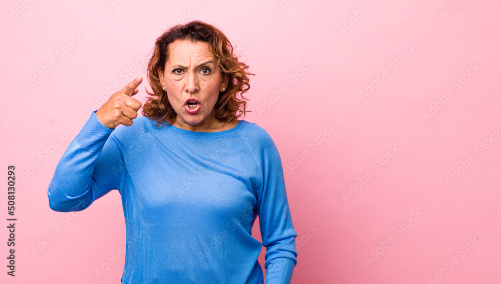 middle age hispanic woman pointing at camera with an angry aggressive ...