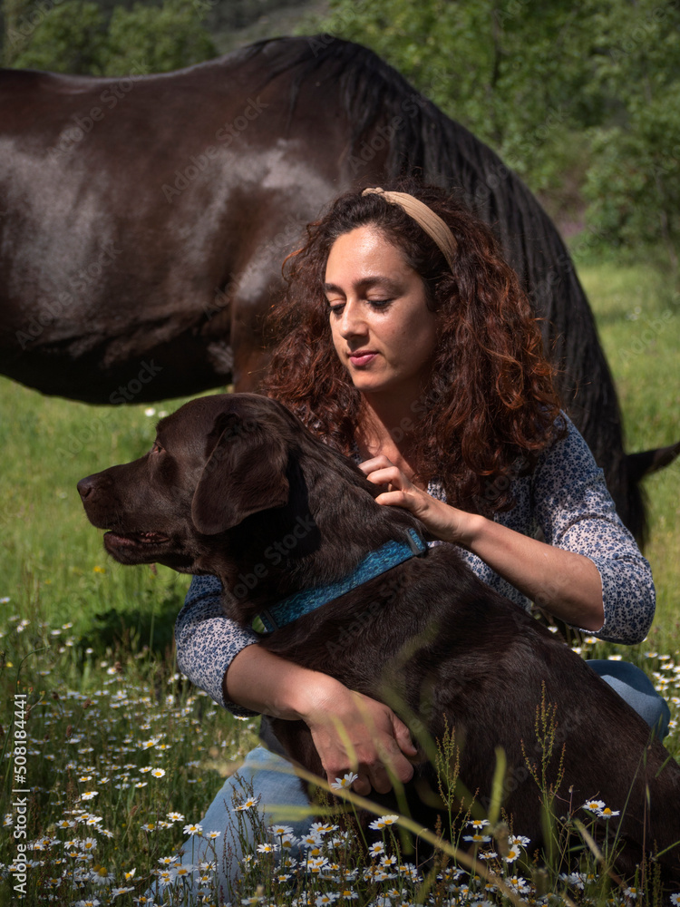 Female with her chocolate labrador retriever in the mountains in spring ...