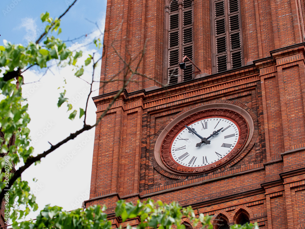 Church clock. Red brick church tower with ancient black and white clock ...