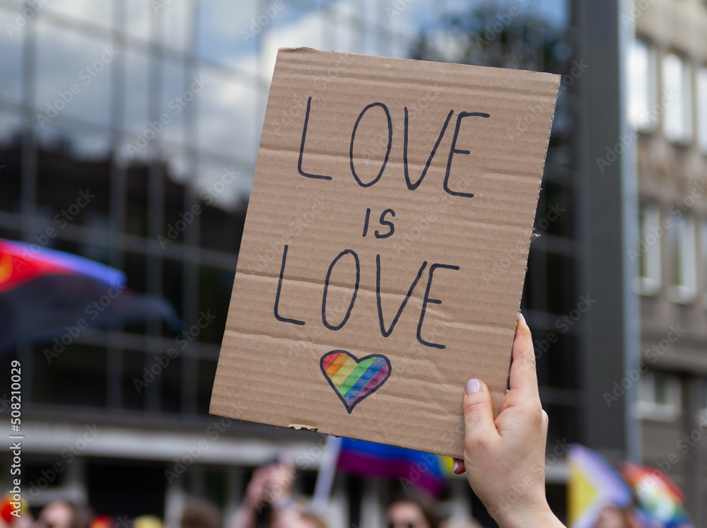 Hand holding placard sign Love is Love with rainbow flag heart, symbol ...