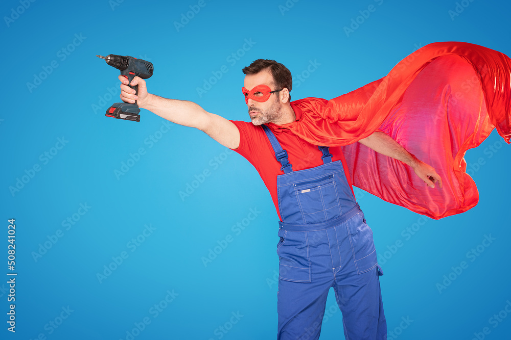 Handsome handyman in red cape and mask as a super hero posing with ...