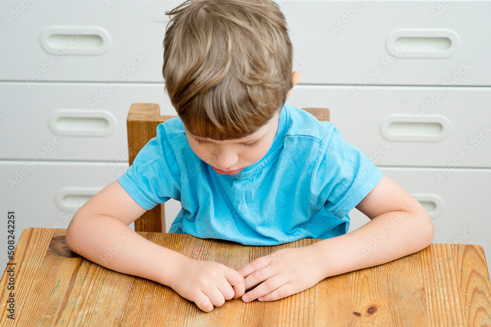 Back to school. Kid sits by the table in nursery or kindergarten ...