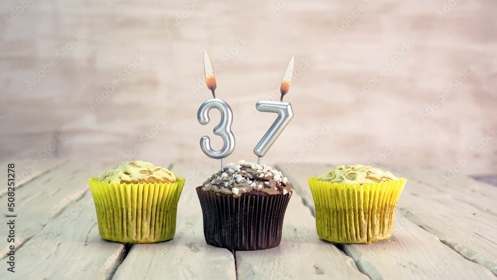 Happy birthday muffins with candles with the number 37. Card copy space ...