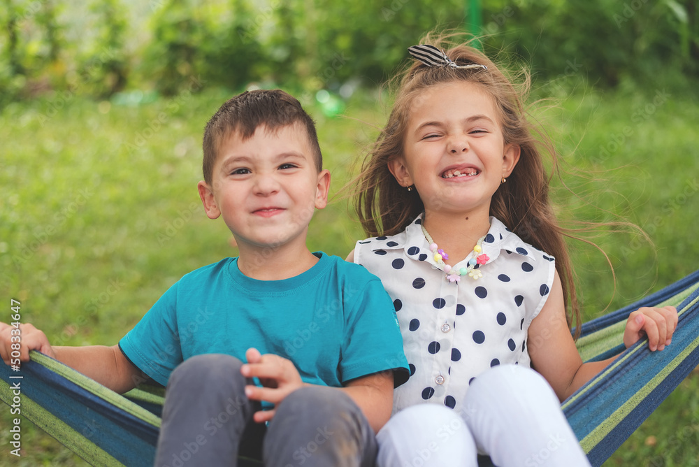 Two happy kids having fun swinging on a hammock in the spring garden ...