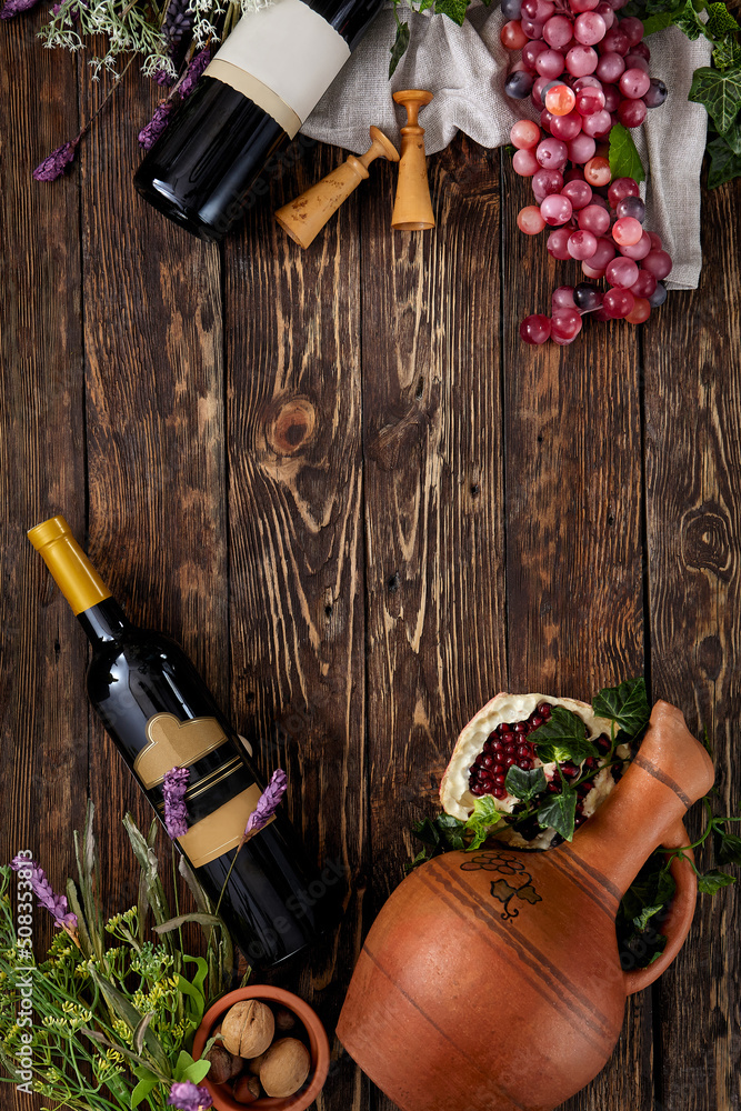 Wine background with bottle, grape and clay jug and grape leafs. Wooden ...