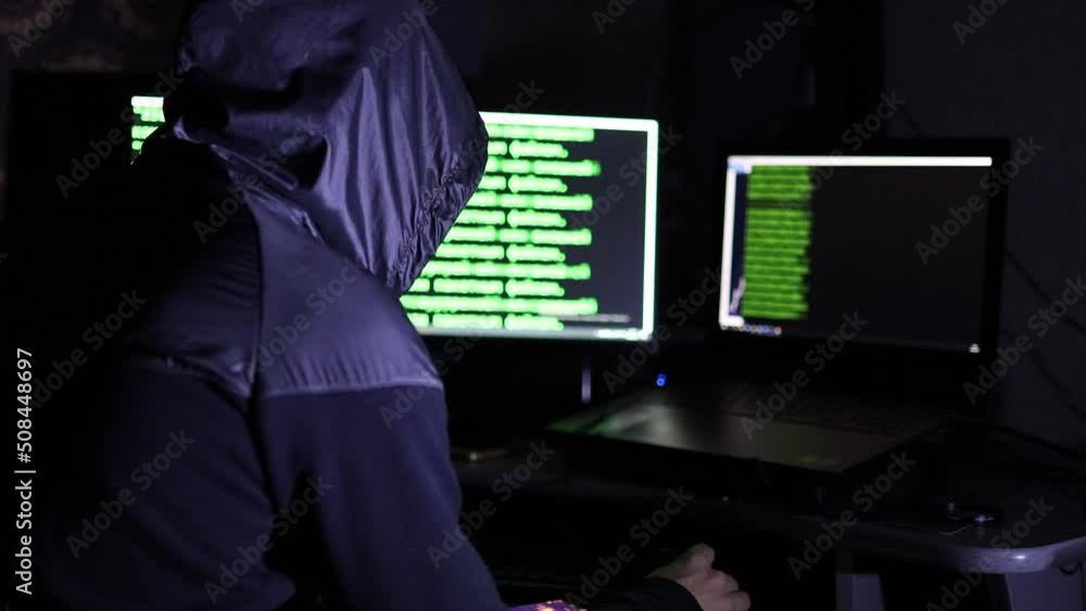 hacker in a dark room is programming a code, there are green symbols on ...