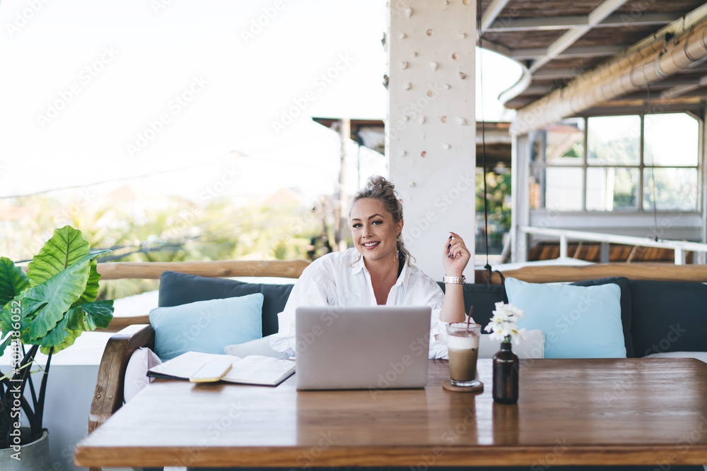 Portrait of millennial female graphic designer looking at camera during ...