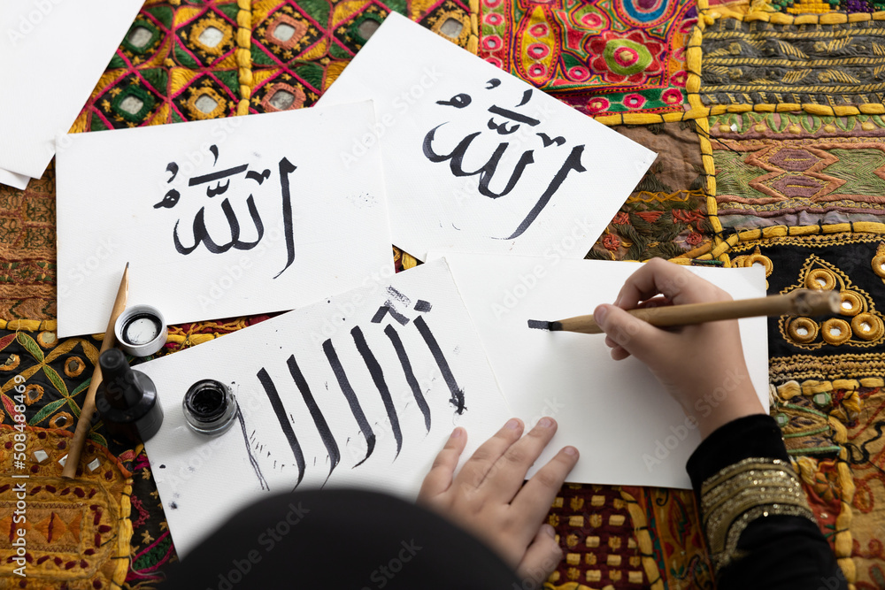 Foto de close up muslim girl hands writing Arabic text with bamboo pens ...