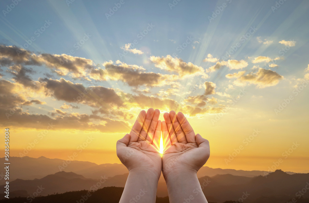 Human hands with bright sunbeam praying to god on mountain sunset ...