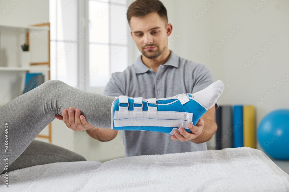 Male traumatologist provides medical care to patient with sprained leg ...