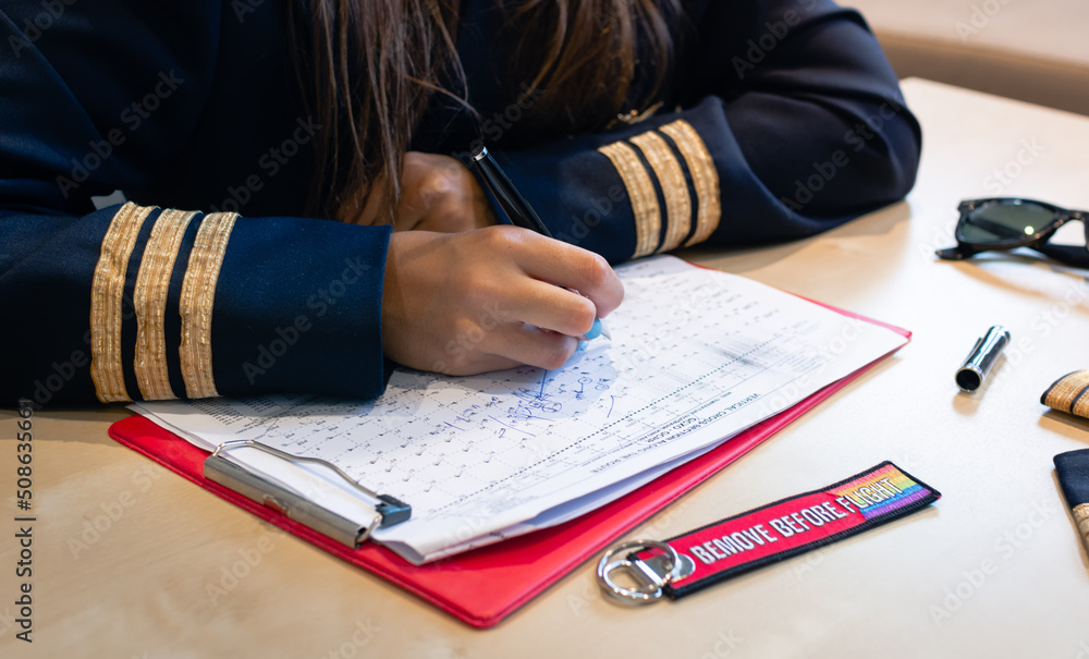 Unrecognizable female pilot preparing flight documentation with a ...