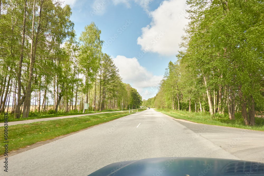 An empty highway (new asphalt road) through the rural area and forest ...