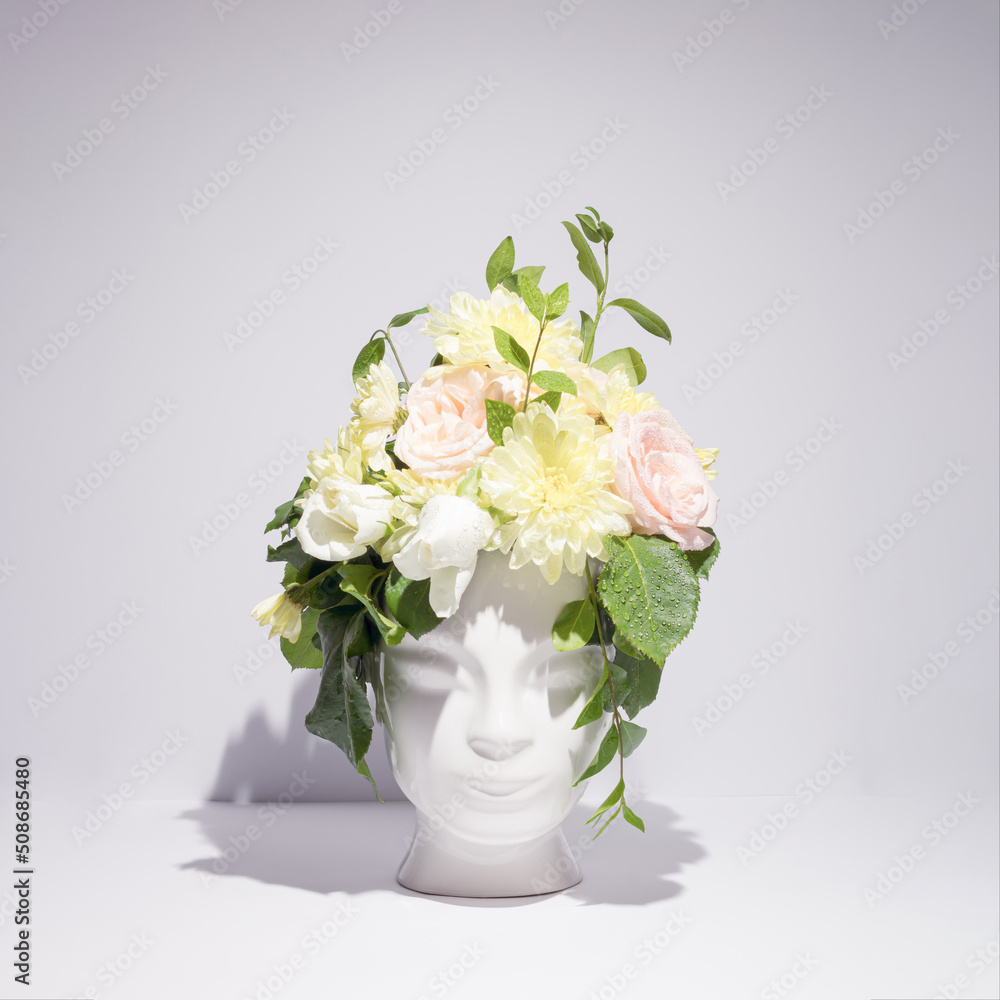 Fresh bunch of colorful flowers in human head shaped vase on grey ...