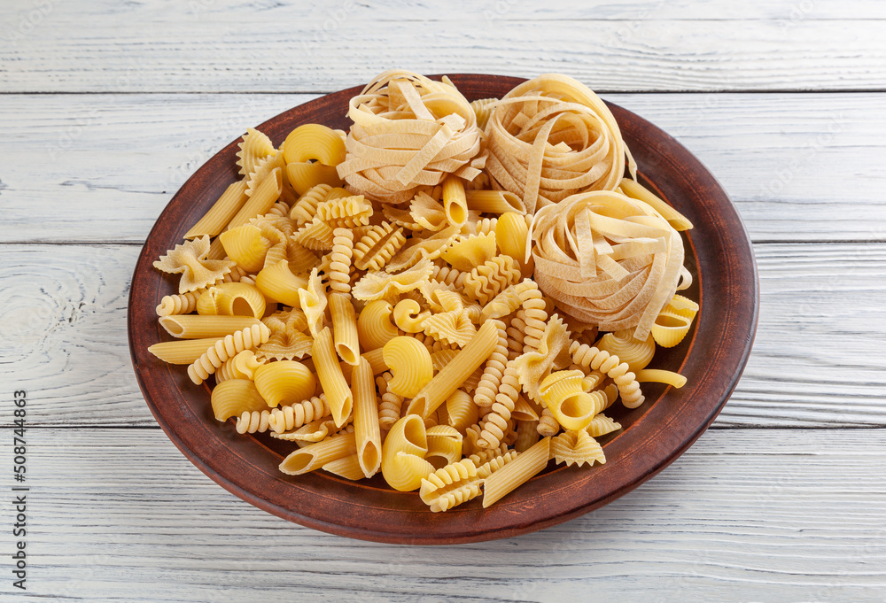 Different types and shapes of Italian pasta in ceramic plate on white ...