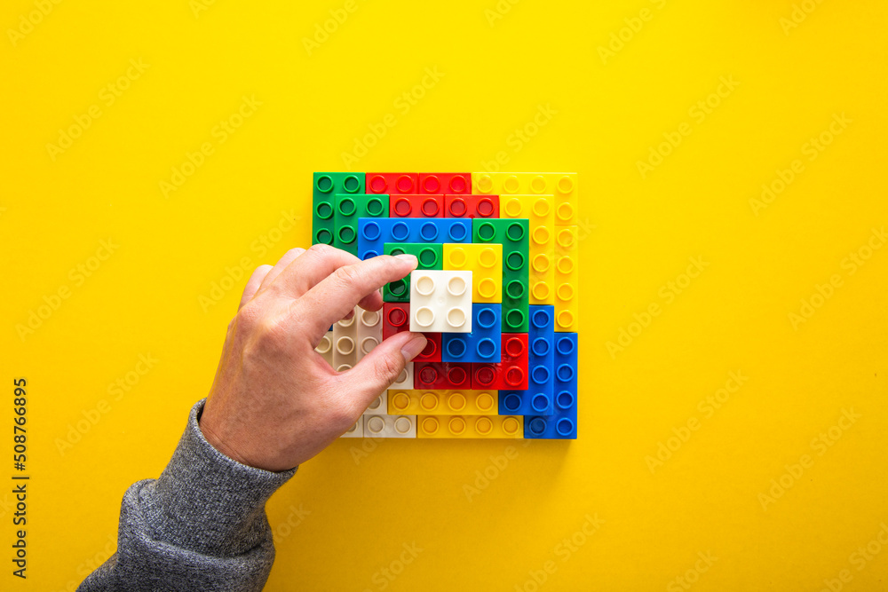 hand stacking up the colorful plastic block on yellow background Stock ...