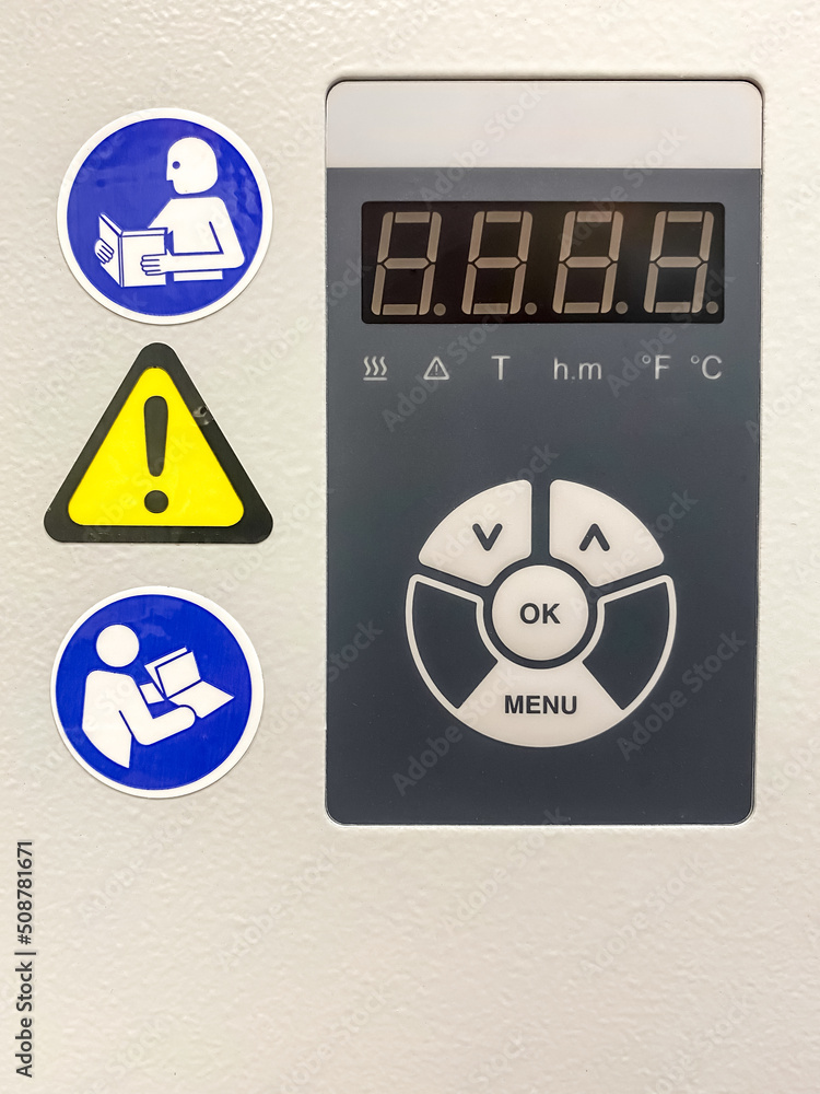 A control panel of a modern laboratory water bath with safety signs ...