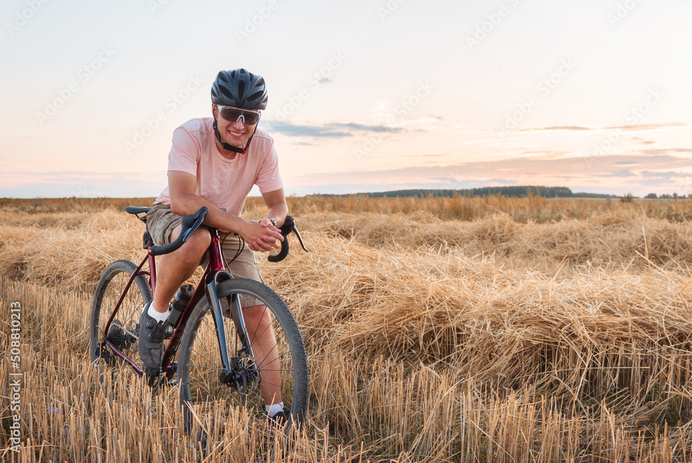 Cyclist stands in the field at sunset. Beautiful landscape with man in ...