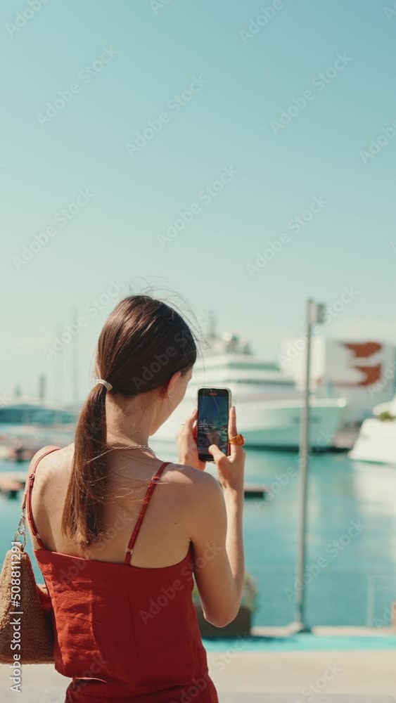 VERTICAL VIDEO: Close-up cute girl takes photos, videos of the seaport ...