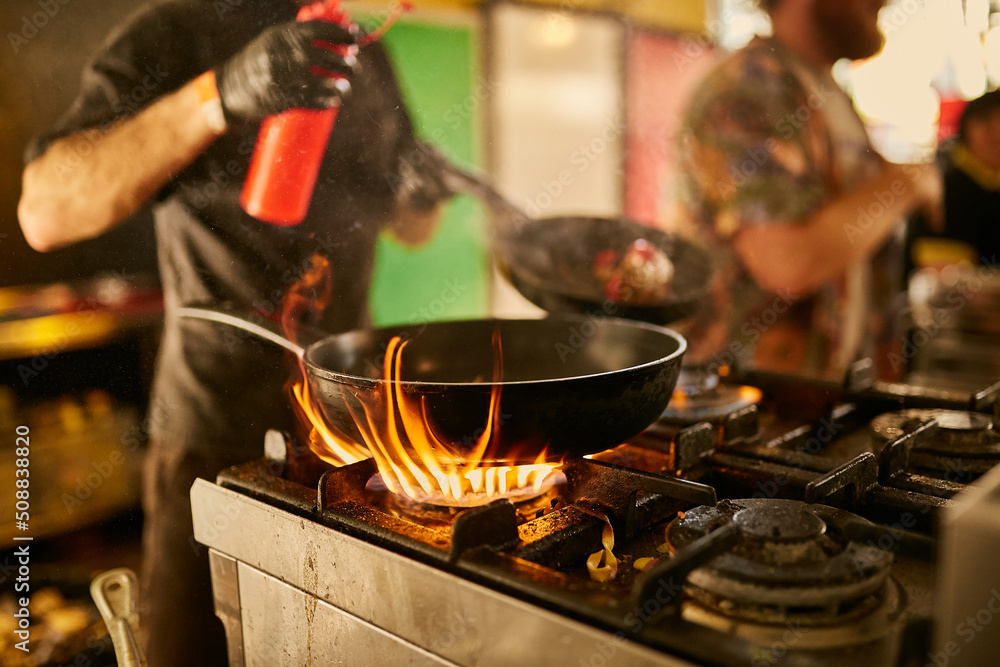 flame in the pan. Professional Chef makes flambe for food in the ...