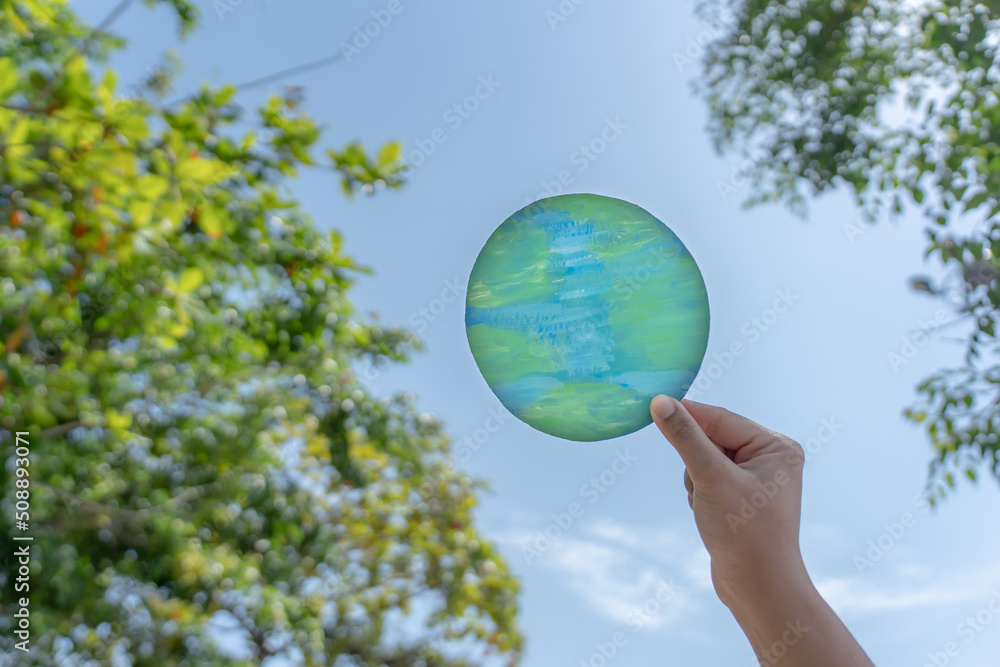 Hand holding earth sign up with natural environment sky and tree as ...