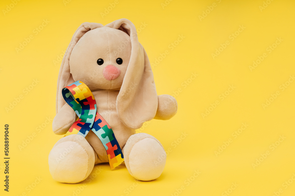 Toy bunny with puzzle pattern ribbon. World autism awareness and pride ...
