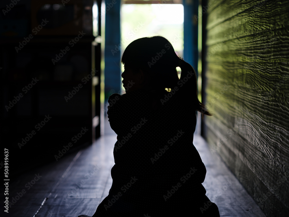 Sad lonely little girl crying while sitting on the floor in dark room ...