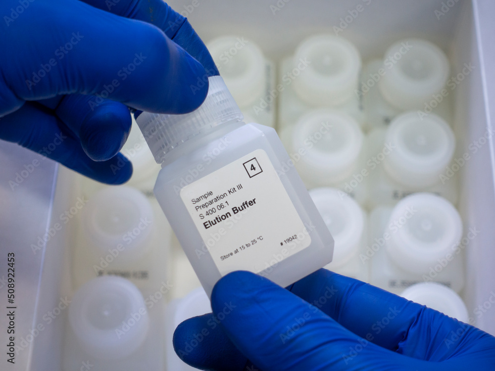 Close-up, two hands in blue gloves hold a white chemical reagent bottle ...