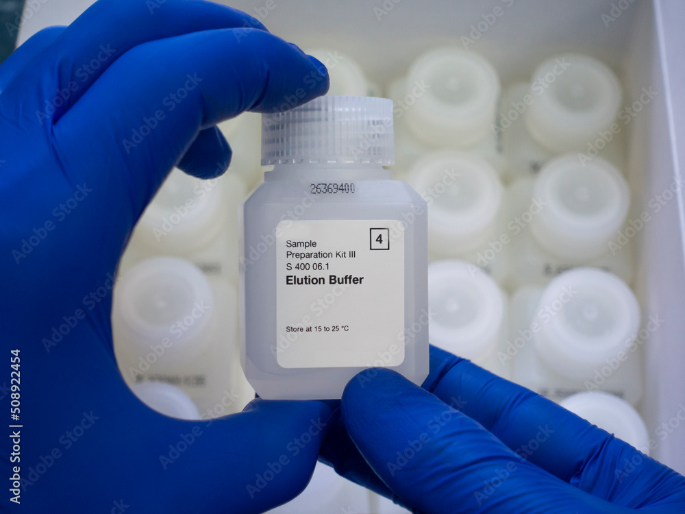 Close-up, two hands in blue gloves hold a white chemical reagent bottle ...