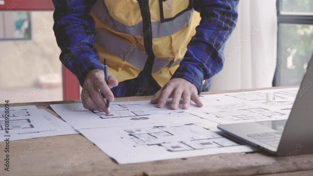 architect reviewing blueprints and holding pencil drawing on desk at ...