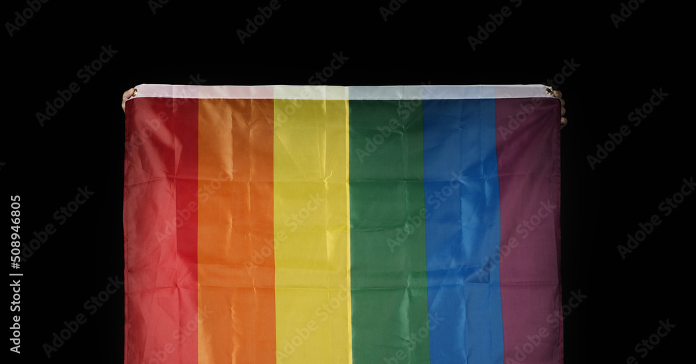 LGBTQ pride flag on black background. Lgbt rainbow flag in gay hand ...