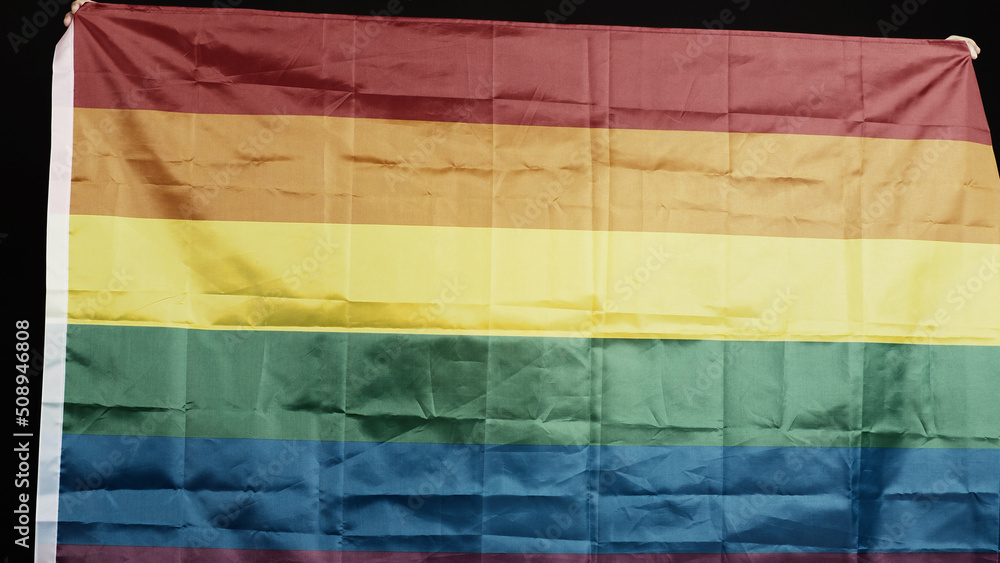 LGBTQ pride flag on black background. Lgbt rainbow flag in gay hand ...