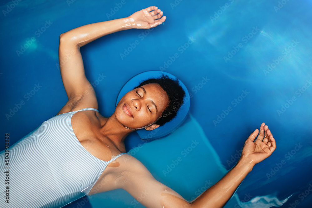 Beautiful middle-aged African American woman floating in tank filled ...