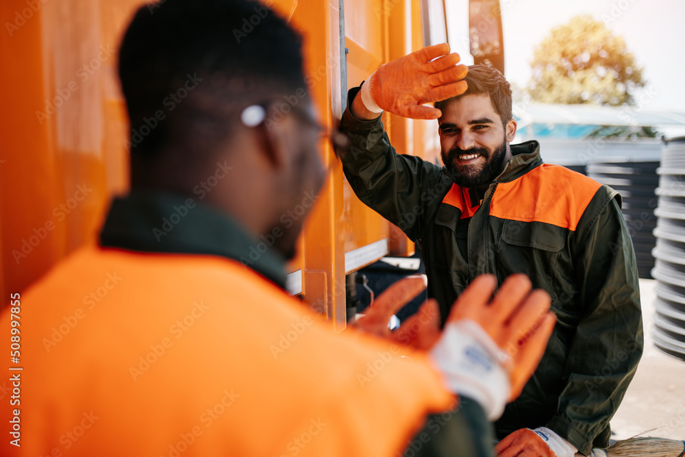 Caucasian and Black young garbage men working together on emptying ...