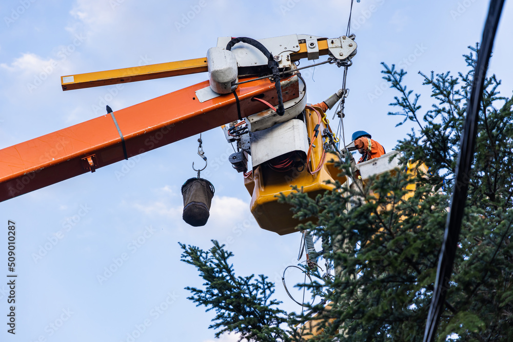 Low angle view of a power line technician at work on an articulated ...