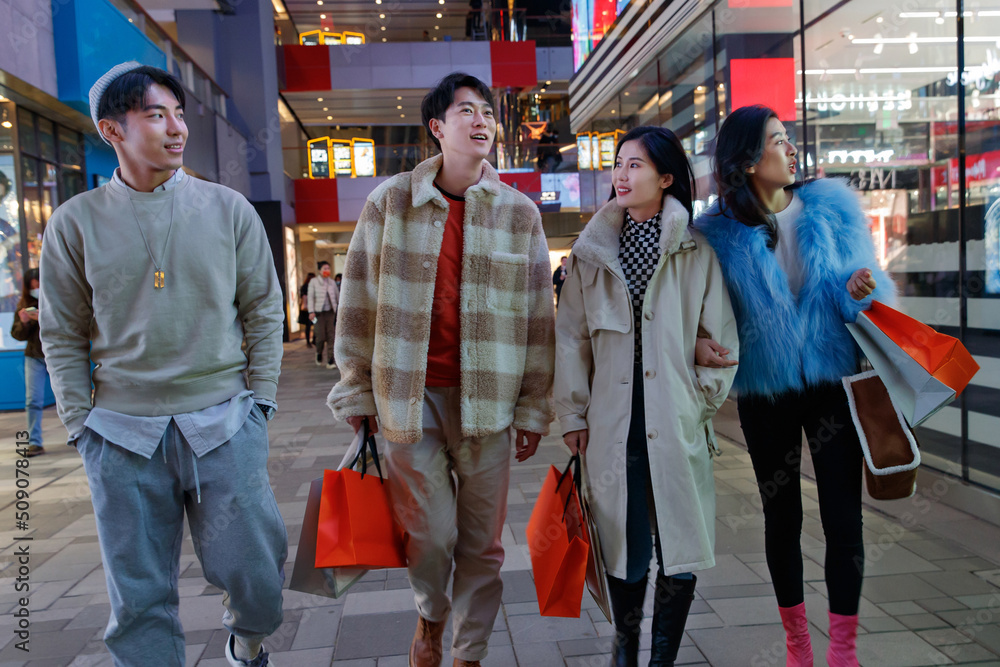 Happy fashionable young people go shopping with holding shopping bags ...