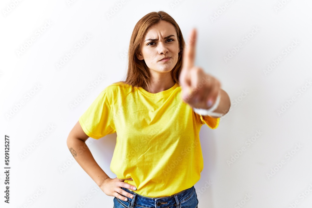 Young brunette woman standing over isolated background pointing with ...