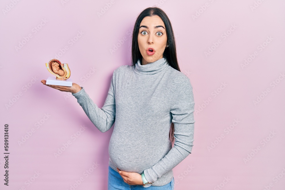 Beautiful woman with blue eyes expecting a baby, holding anatomic fetus ...