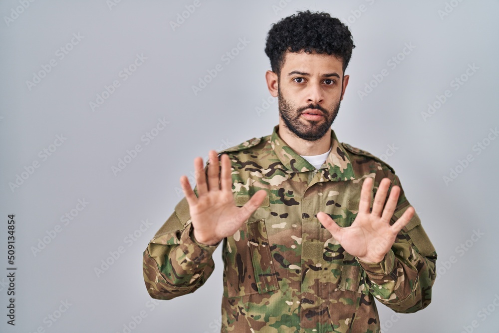 Arab man wearing camouflage army uniform moving away hands palms ...