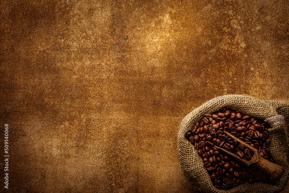 Coffee beans in burlap sack over horizontal grunge background with copy ...